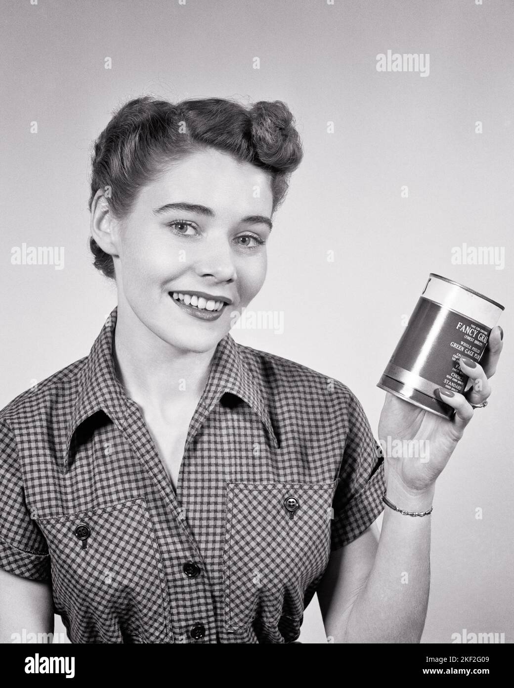 1950s BRUNETTE WOMAN SPOKESPERSON HOLDING TIN OF CANNED FOOD LOOKING AT ...