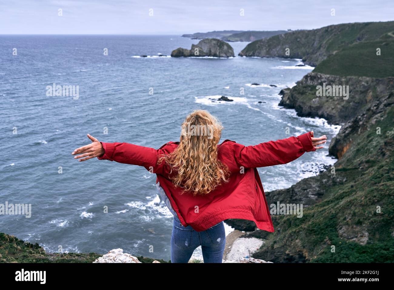 blond caucasian girl with red jacket and blue pants standing with her ...
