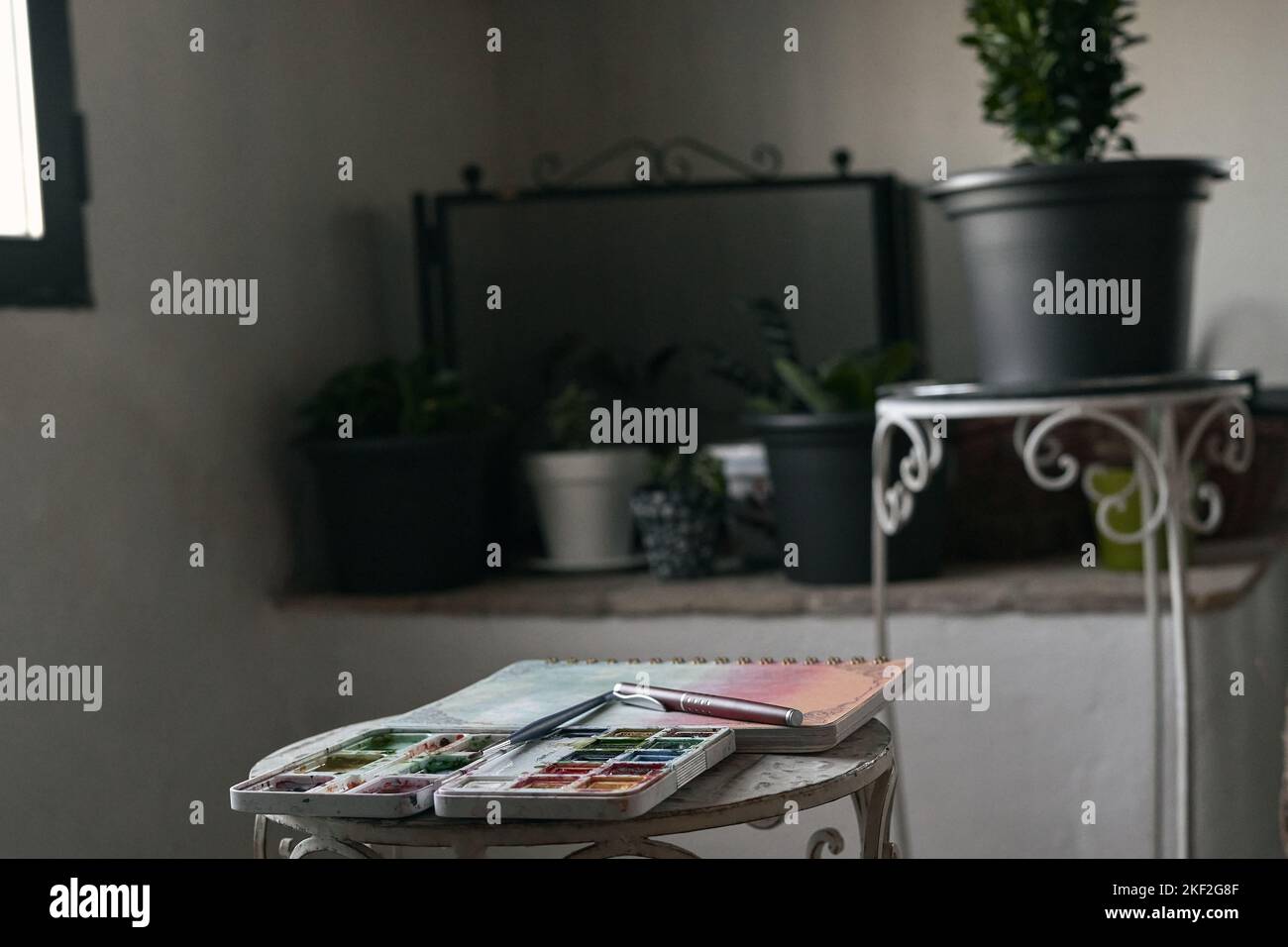 dirty color palette box of watercolors with brush and fountain pen next ...