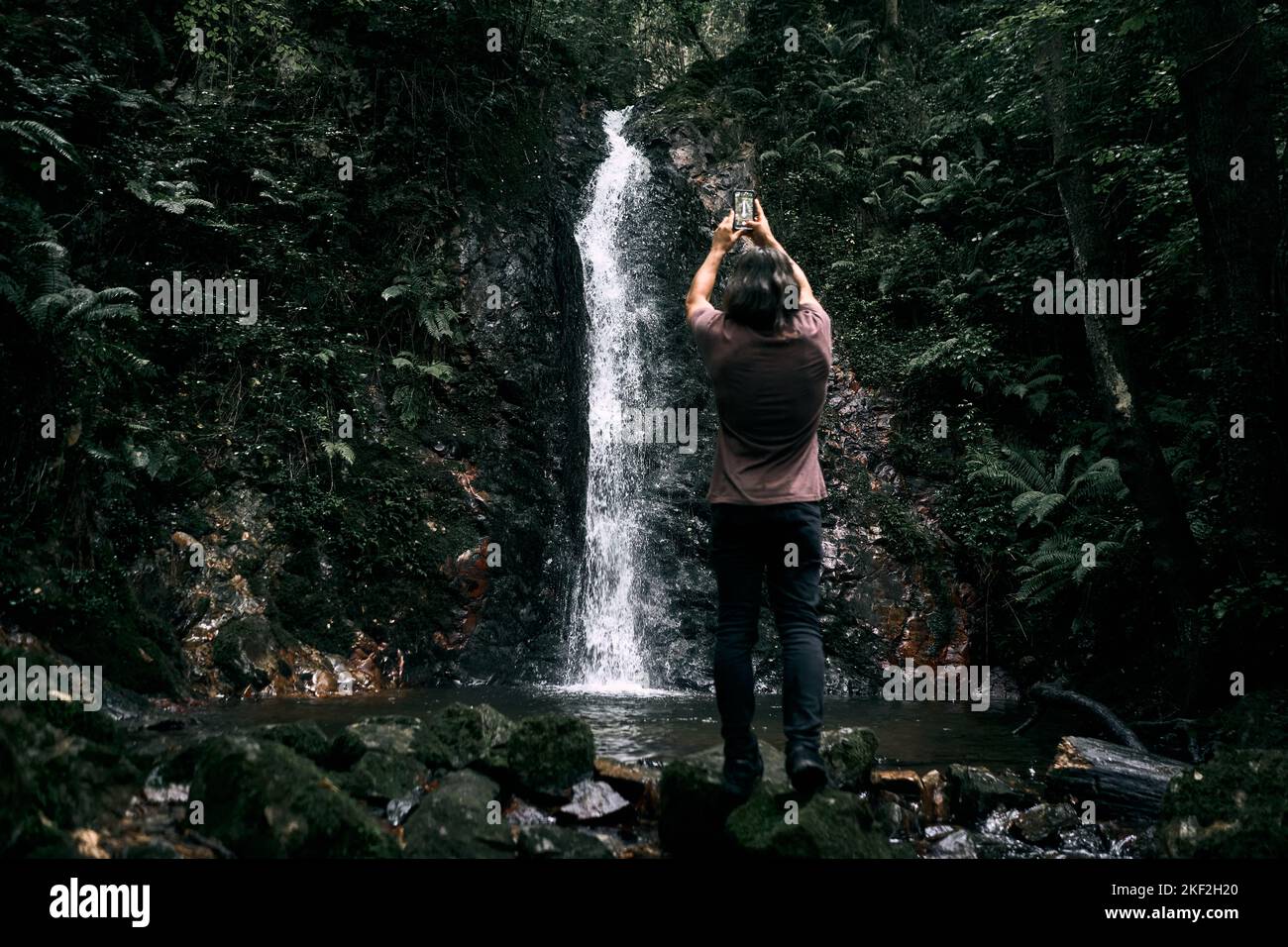 brunette caucasian boy with long hair standing on a lonely rock by the ...