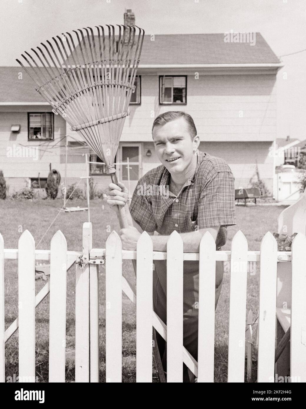1950s SMILING MAN HOMEOWNER LOOKING AT CAMERA HOLDING LEAF RAKE ...