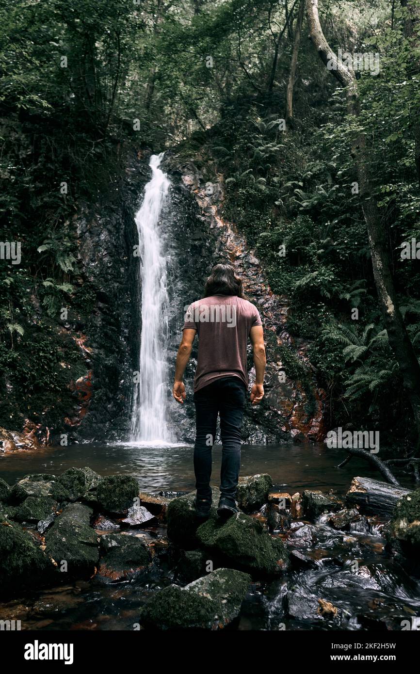long-haired caucasian boy standing on a rock contemplating the beauty ...