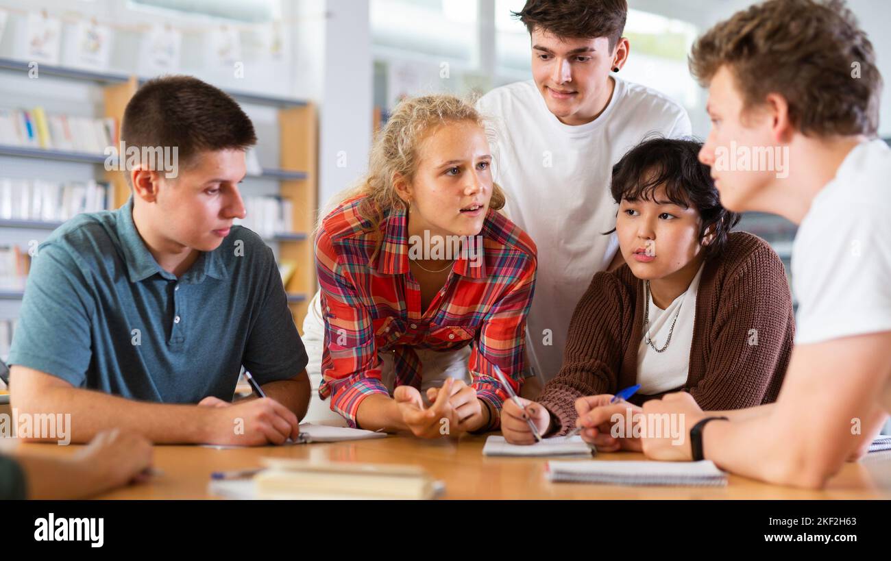Group of schoolchildren in the school library, discussing something ...