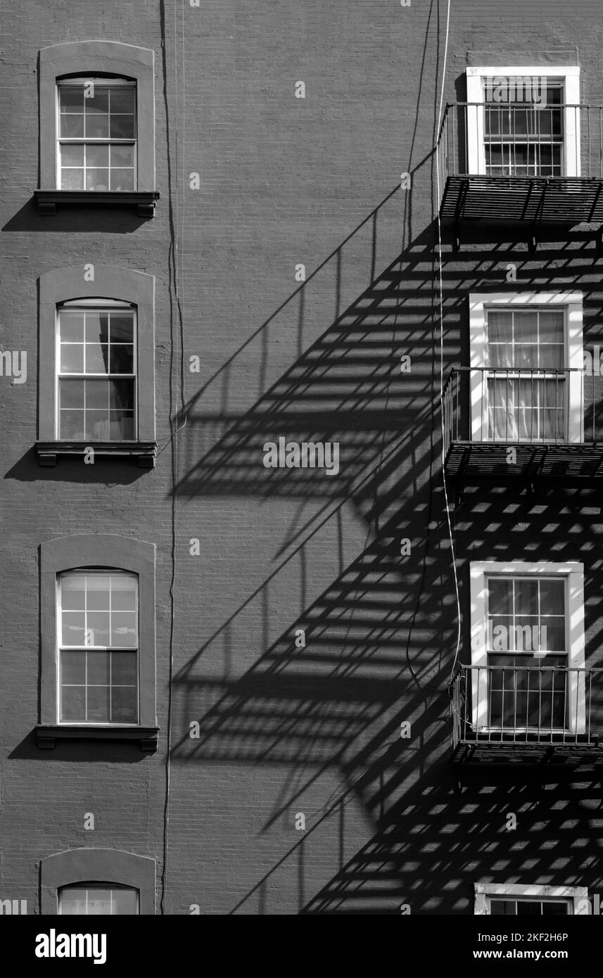 Shadow of fire escapes on the wall of a small apartment building on ...