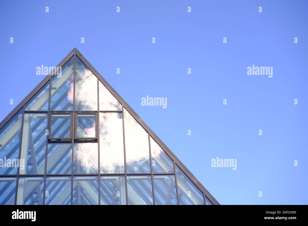 Glass roof over retail complex. White, fluffy clouds reflecting in ...