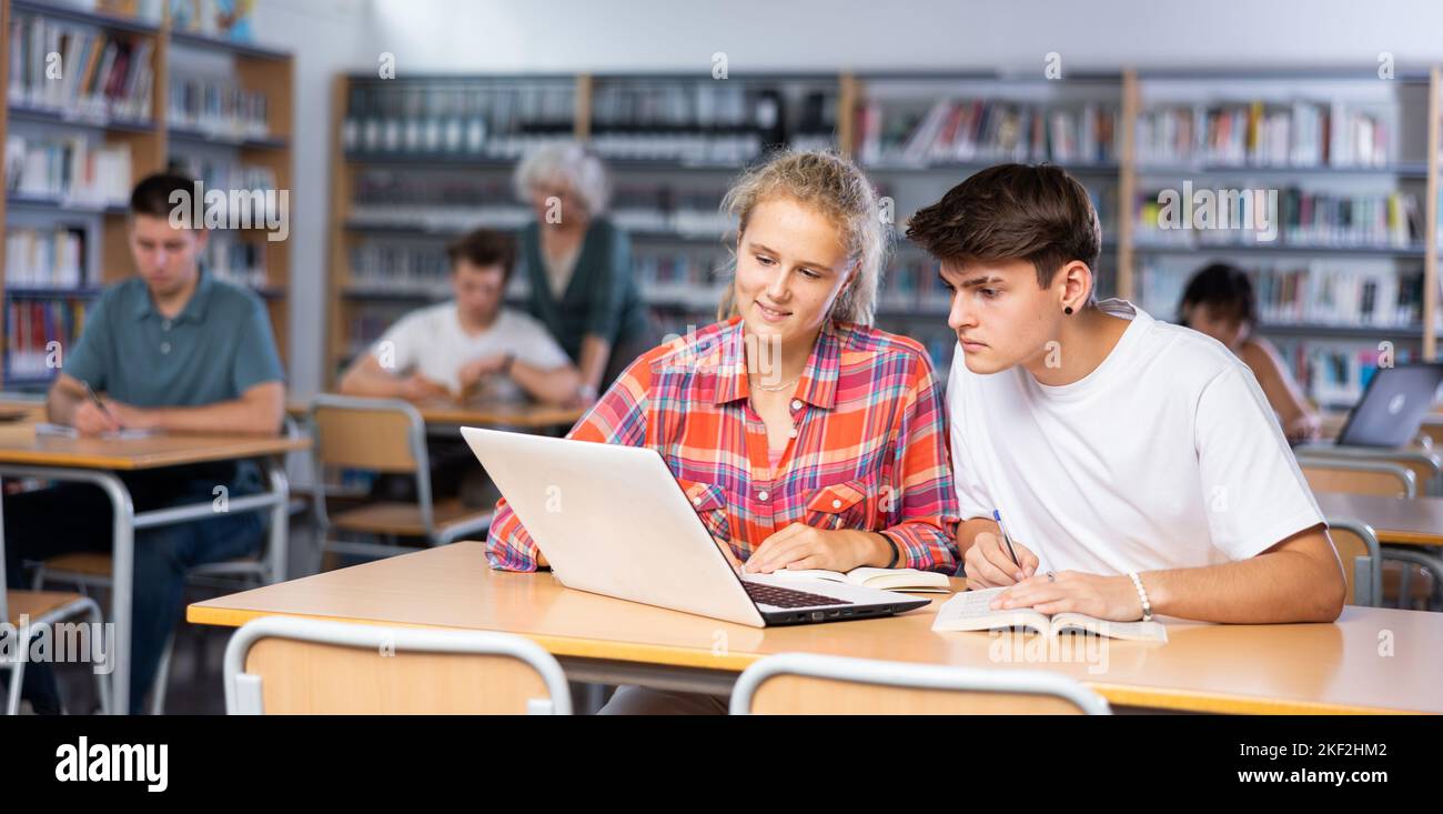 Positive female and male students teenagers study together at laptop ...
