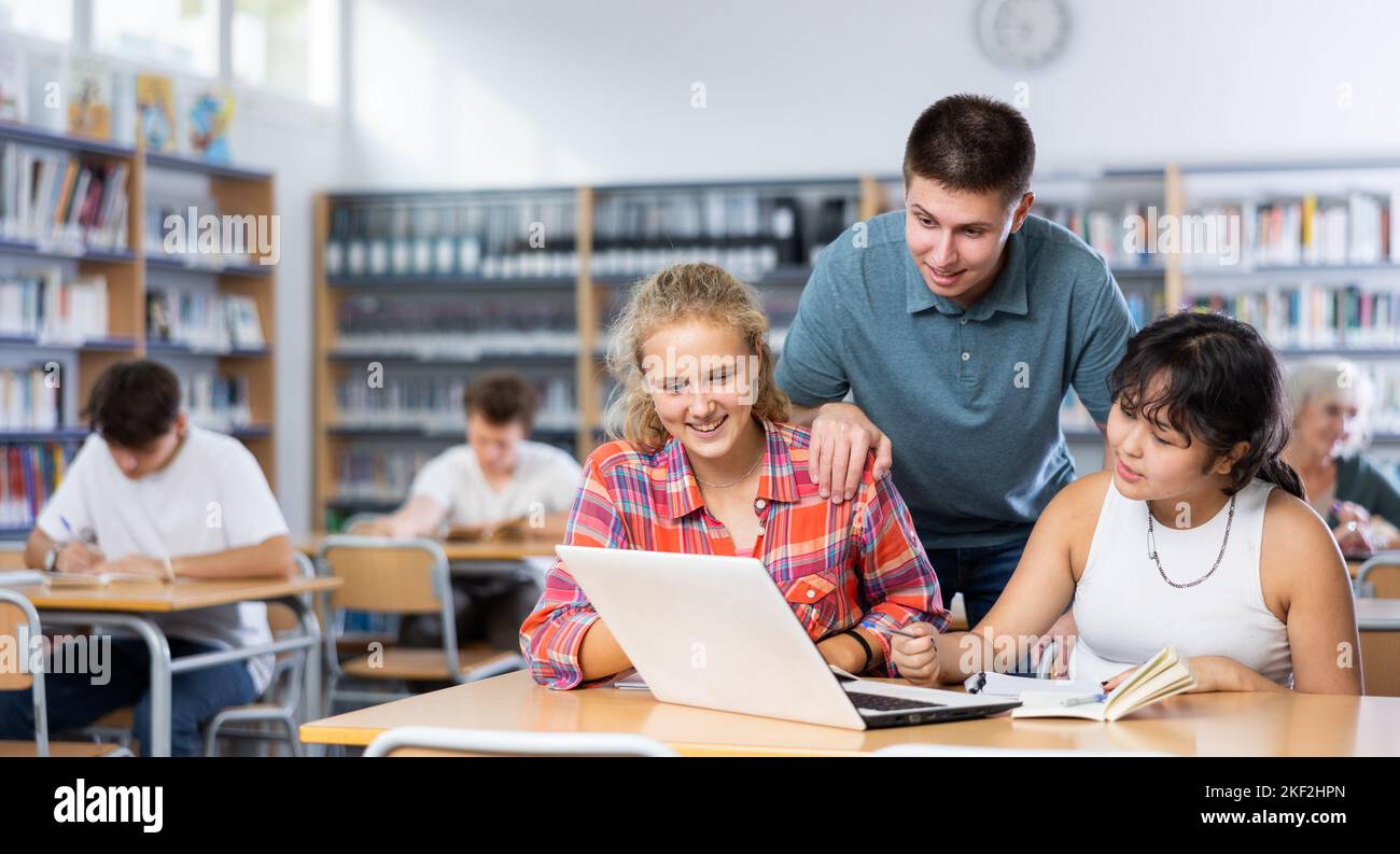 Schoolchildren help each other solve the task in school library Stock ...