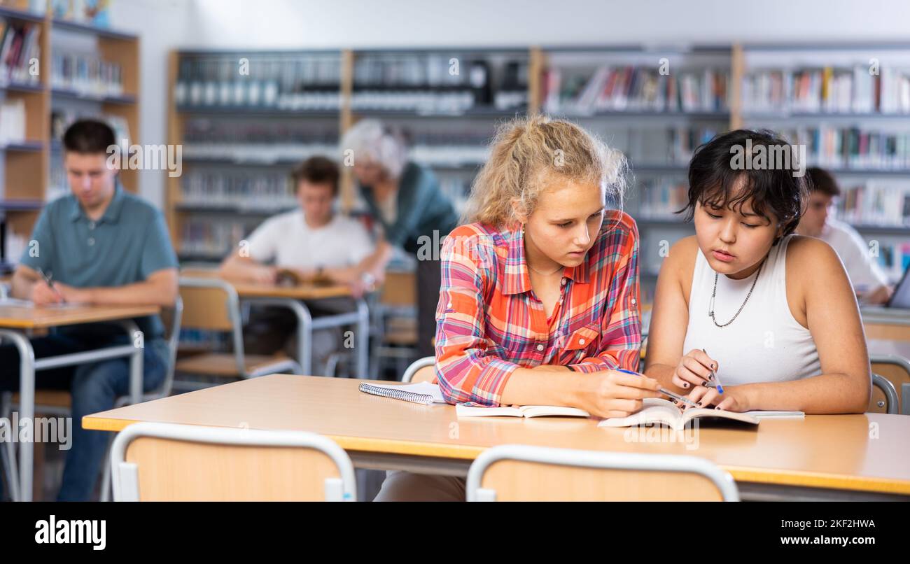 Two schoolgirls reading books and taking abstract in copybooks Stock ...