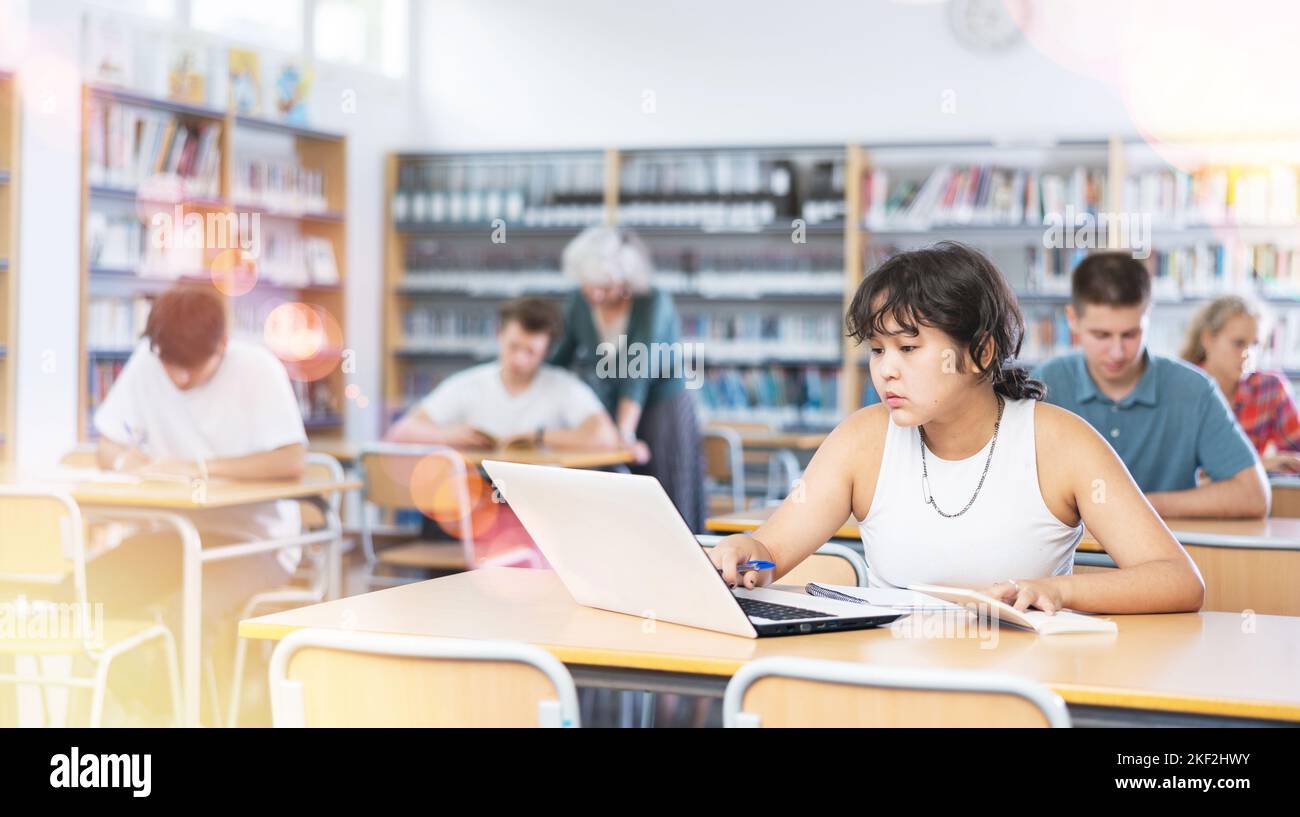Schoolgirl studies on a laptop and writes notes in a copybook Stock ...