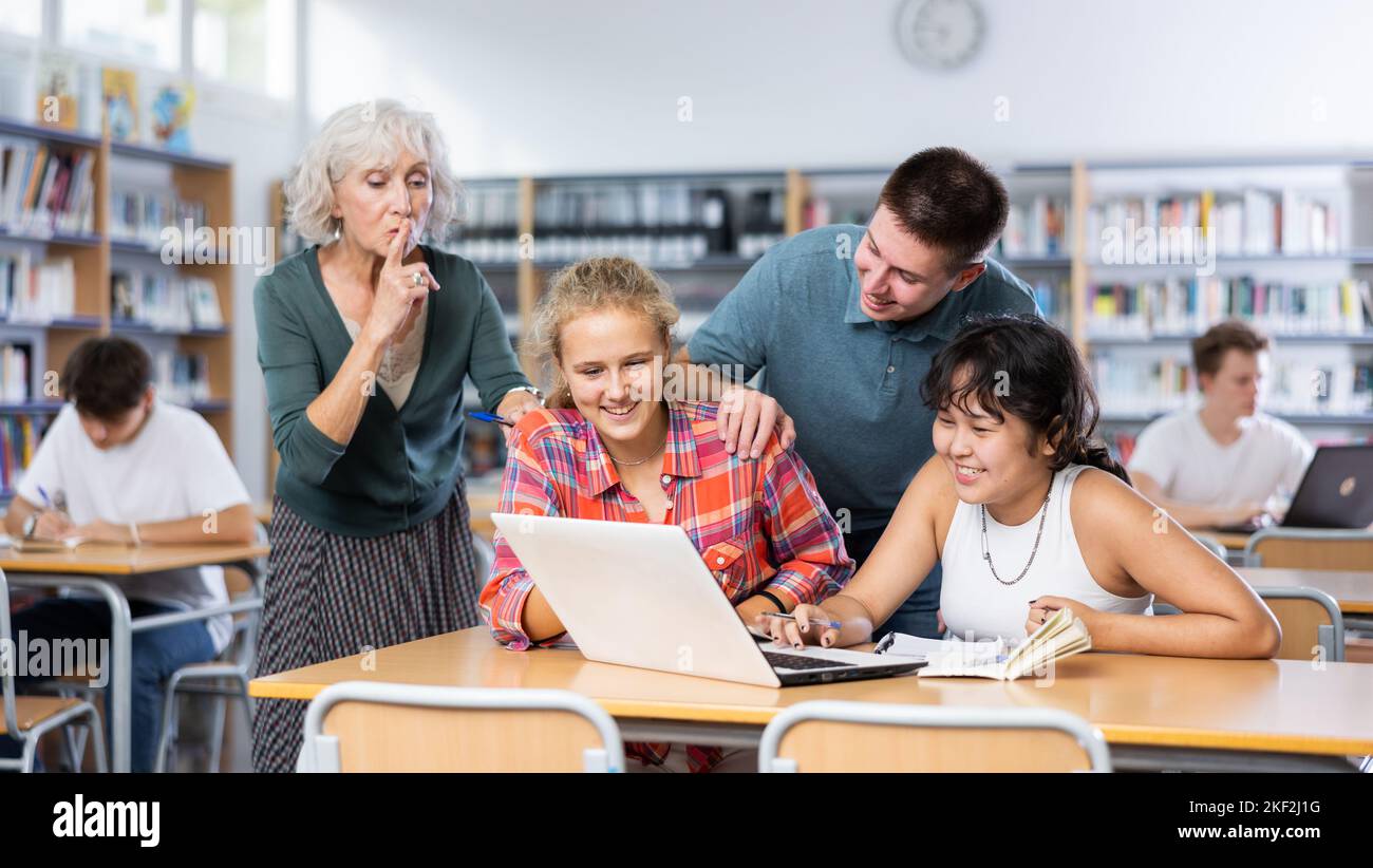 Mature female teacher makes shh sound asks teenage students to be quiet ...