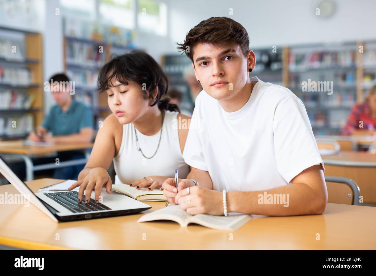 Boy and girl study together at laptop while sitting in school library ...