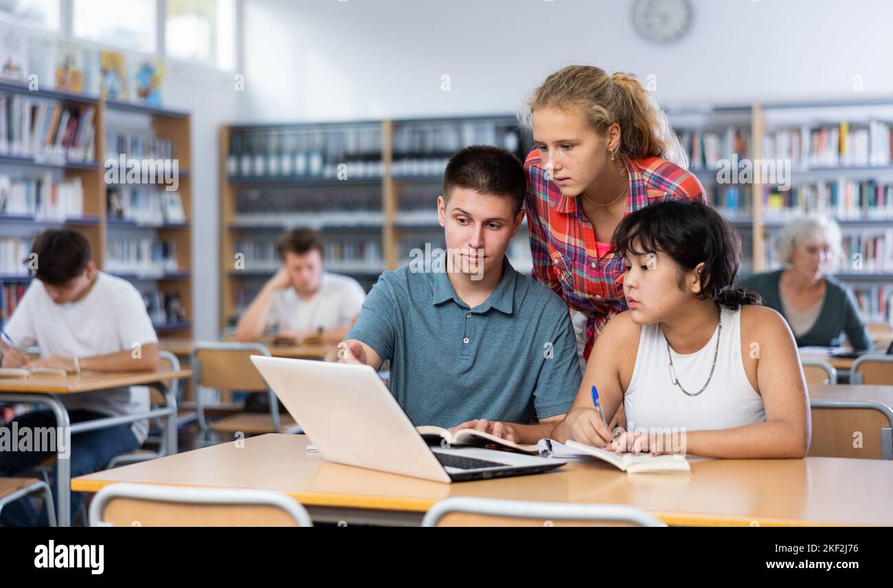 Schoolchildren help each other solve the task in school library Stock ...