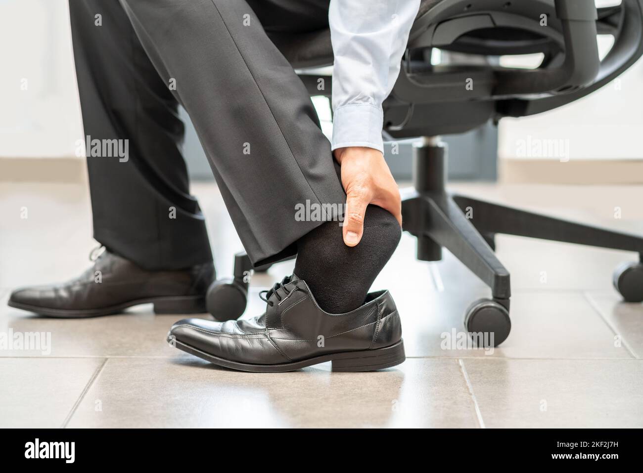 Closeup of business man touching feet with his hand at office Stock ...