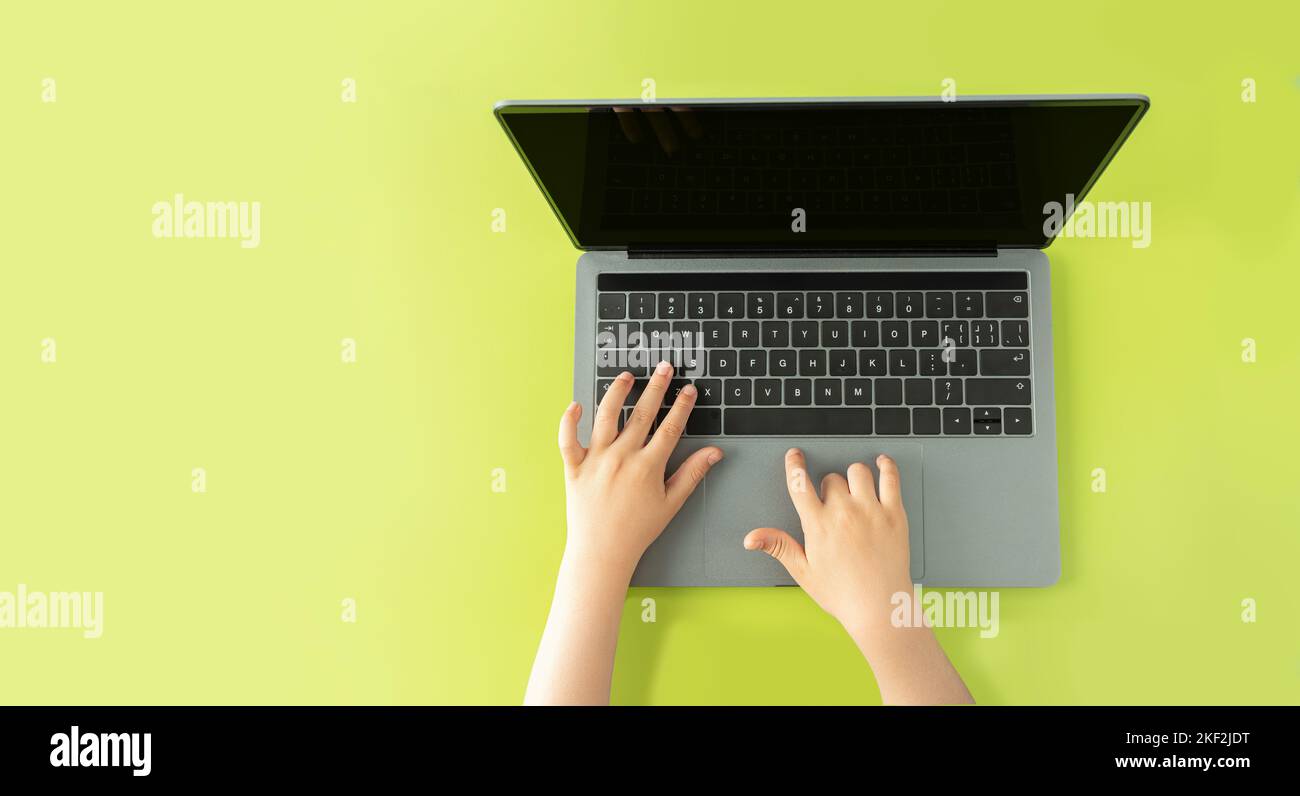 High angle shot of a little kid using a laptop on green background with ...