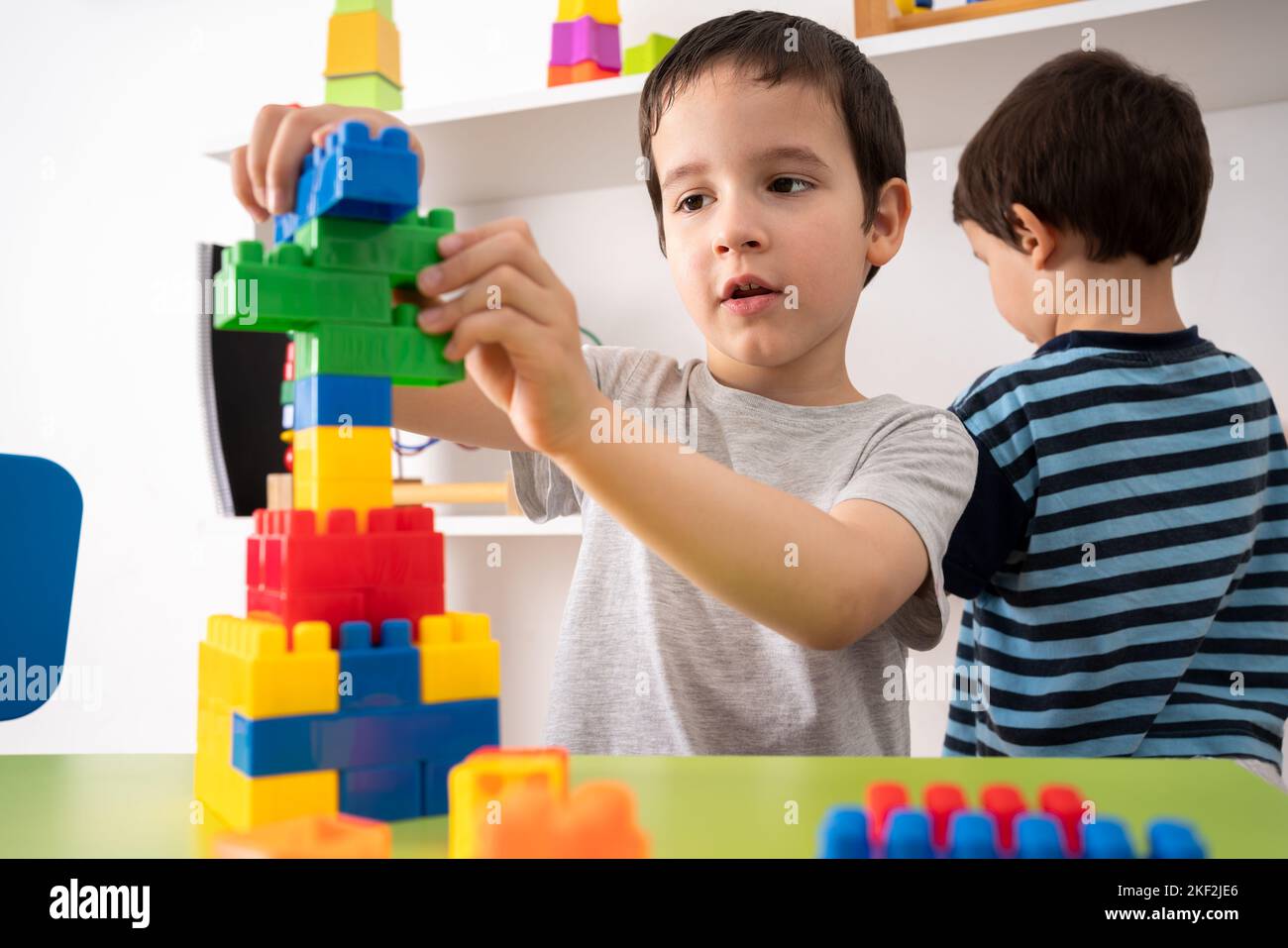 Little boy playing with colourful educational toy blocks on the table ...