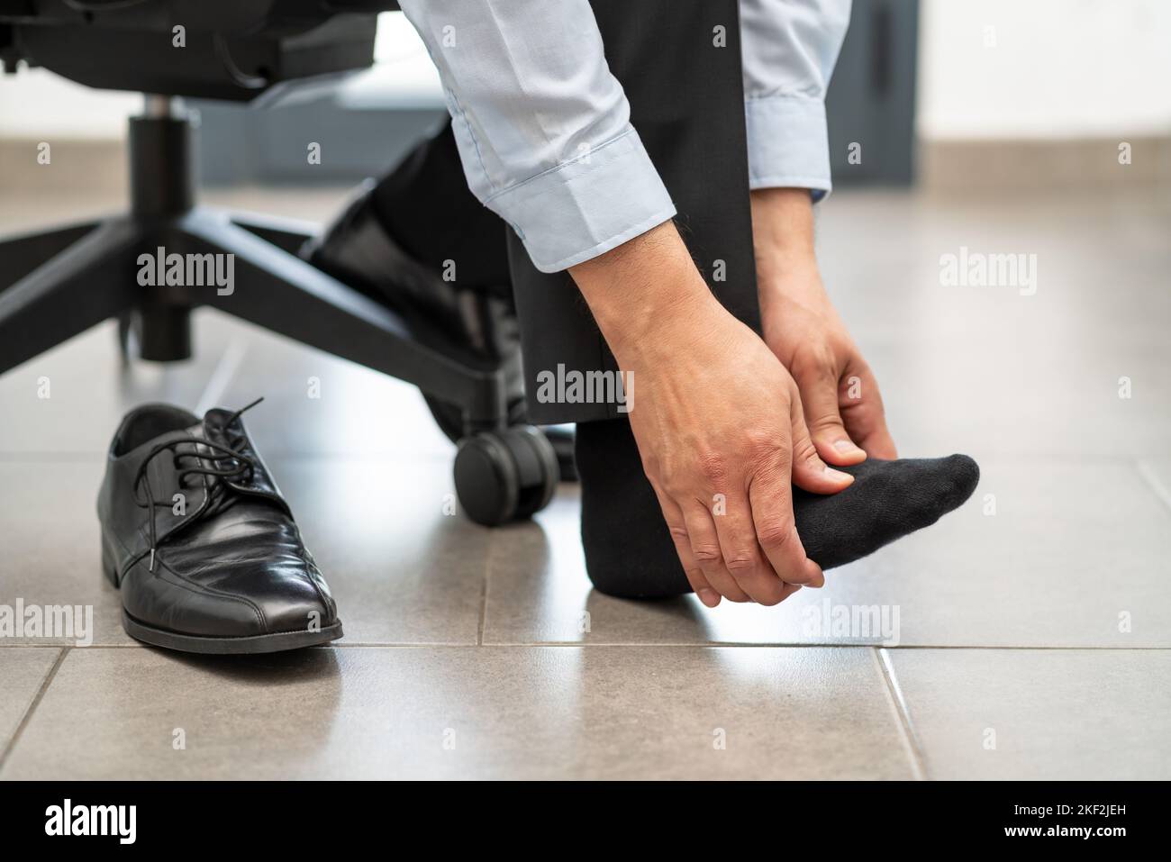 Business man touching feet with his hand at office Stock Photo - Alamy