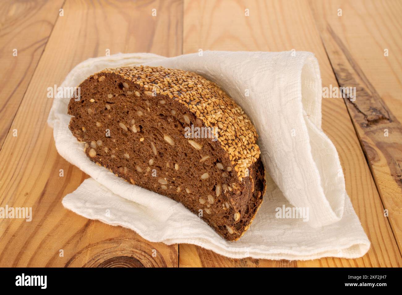 One half of rye multigrain bread with linen white napkin on wooden ...