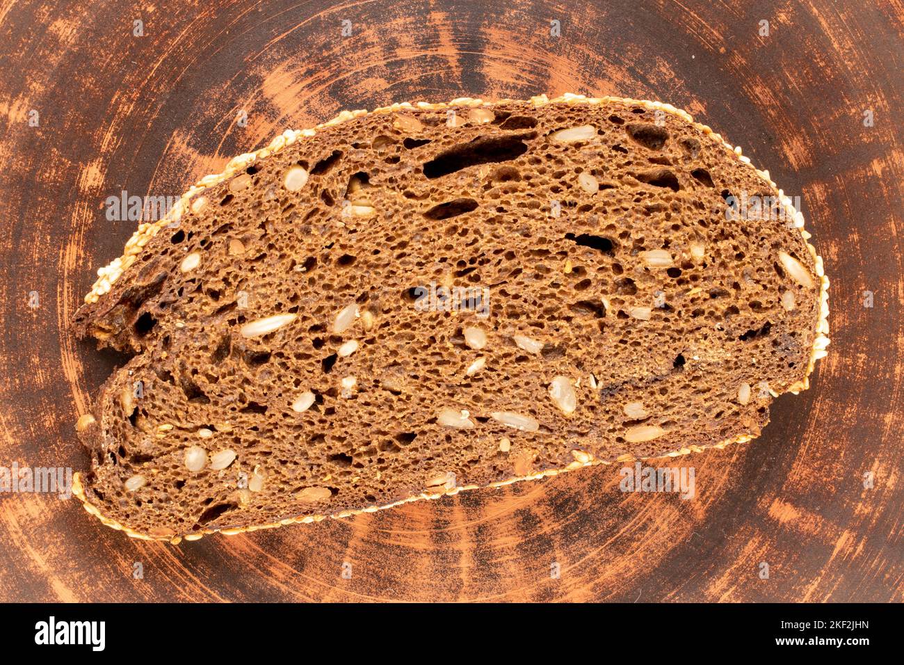 One piece of rye multigrain bread on a clay plate, macro, top view ...