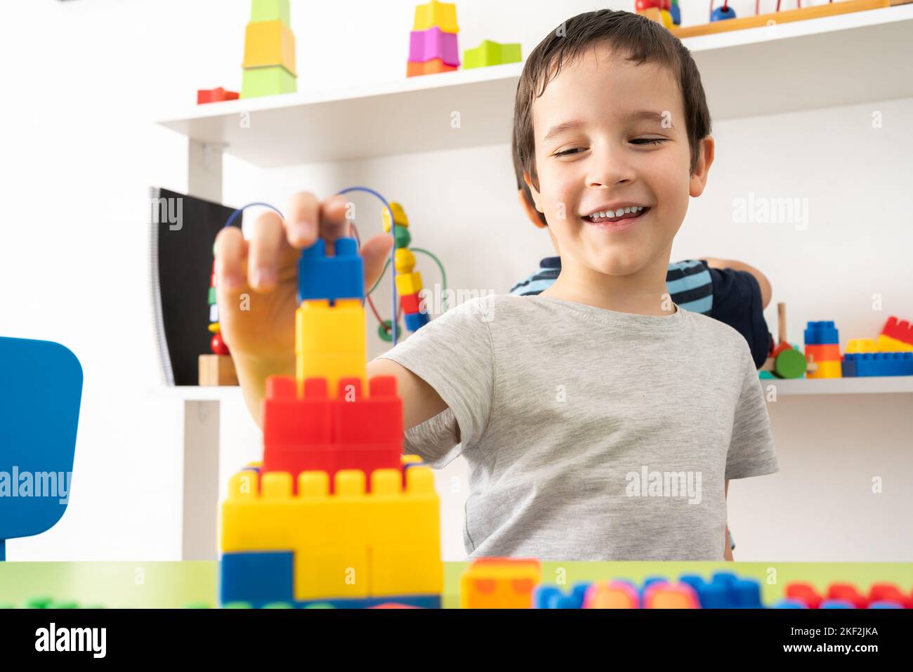 Little boy playing with colourful educational toy blocks on the table ...