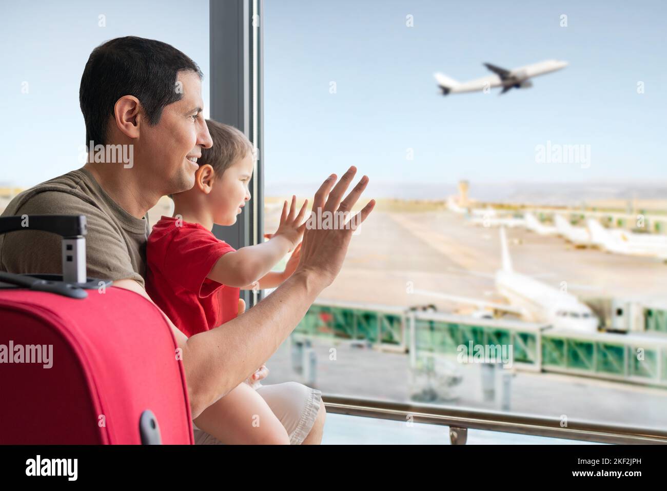 Rear view of a family looking and waving through the window to a plane ...