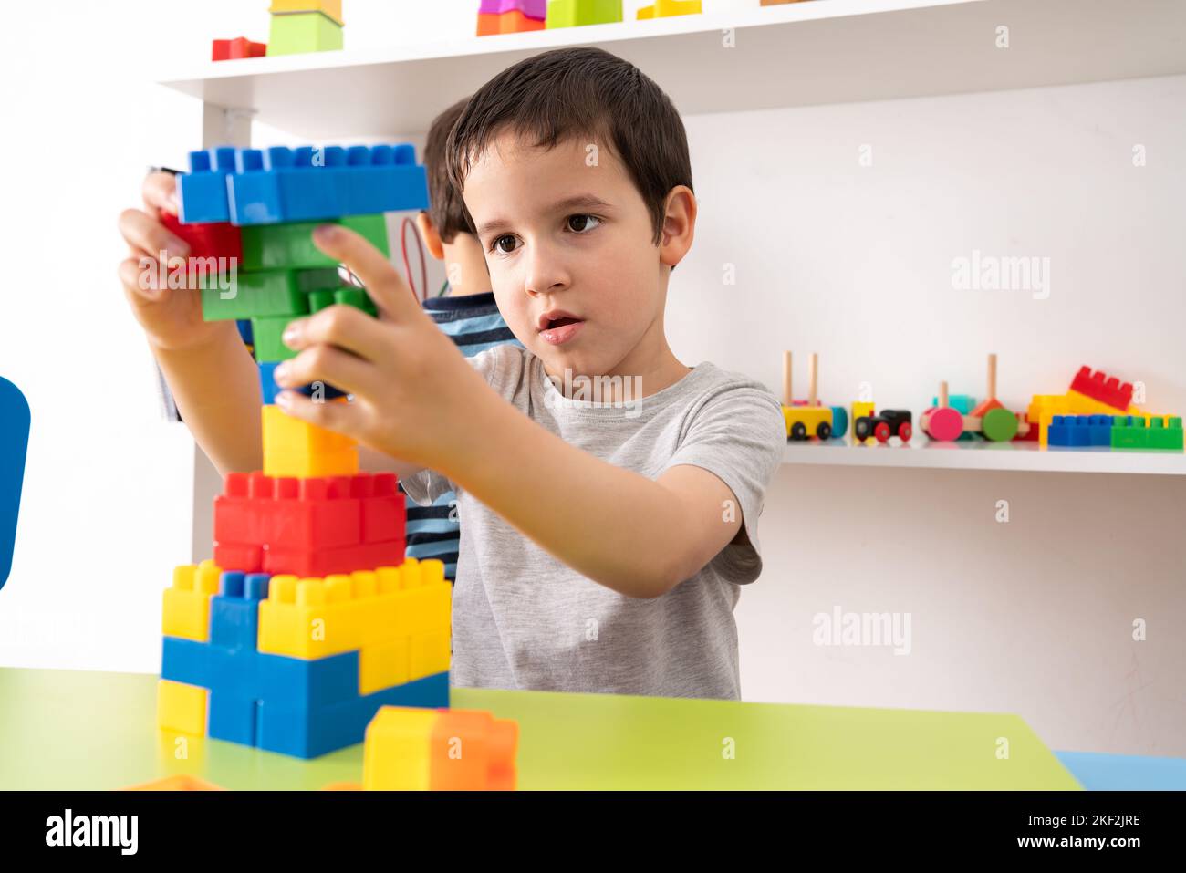 Little boy playing with colourful educational toy blocks on the table ...