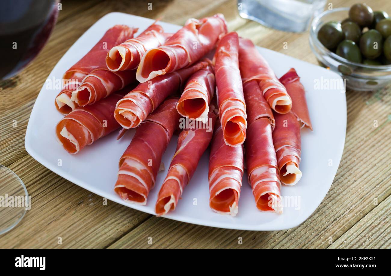 Traditional Spanish meal - rolls of iberian jamon served at plate Stock ...