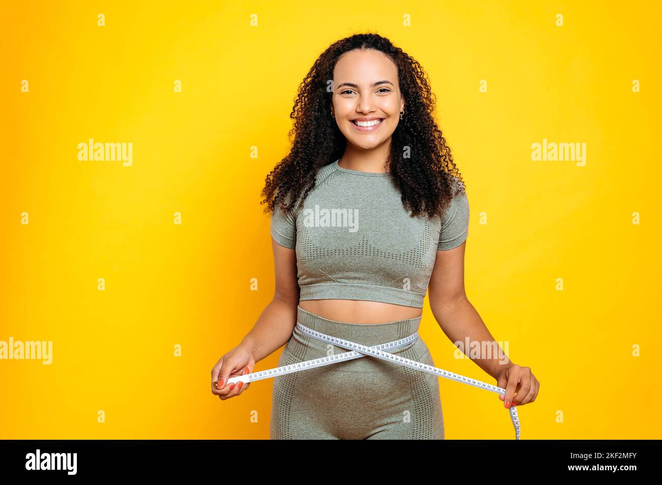 Positive lovely sporty mixed race young woman, in sports outfit, stand ...