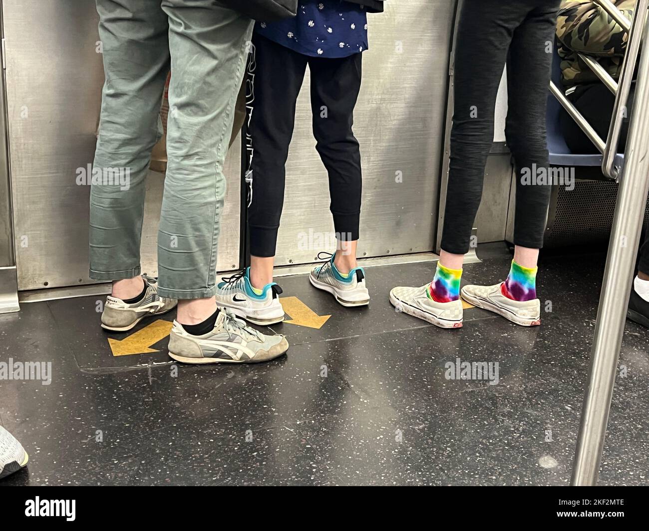 Legs of young women in running shoes on a subway train in New York City ...