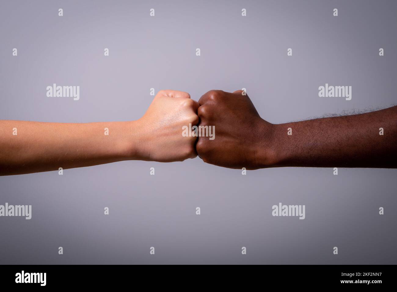 Two fists, one white and one black touching, concept of fight against ...