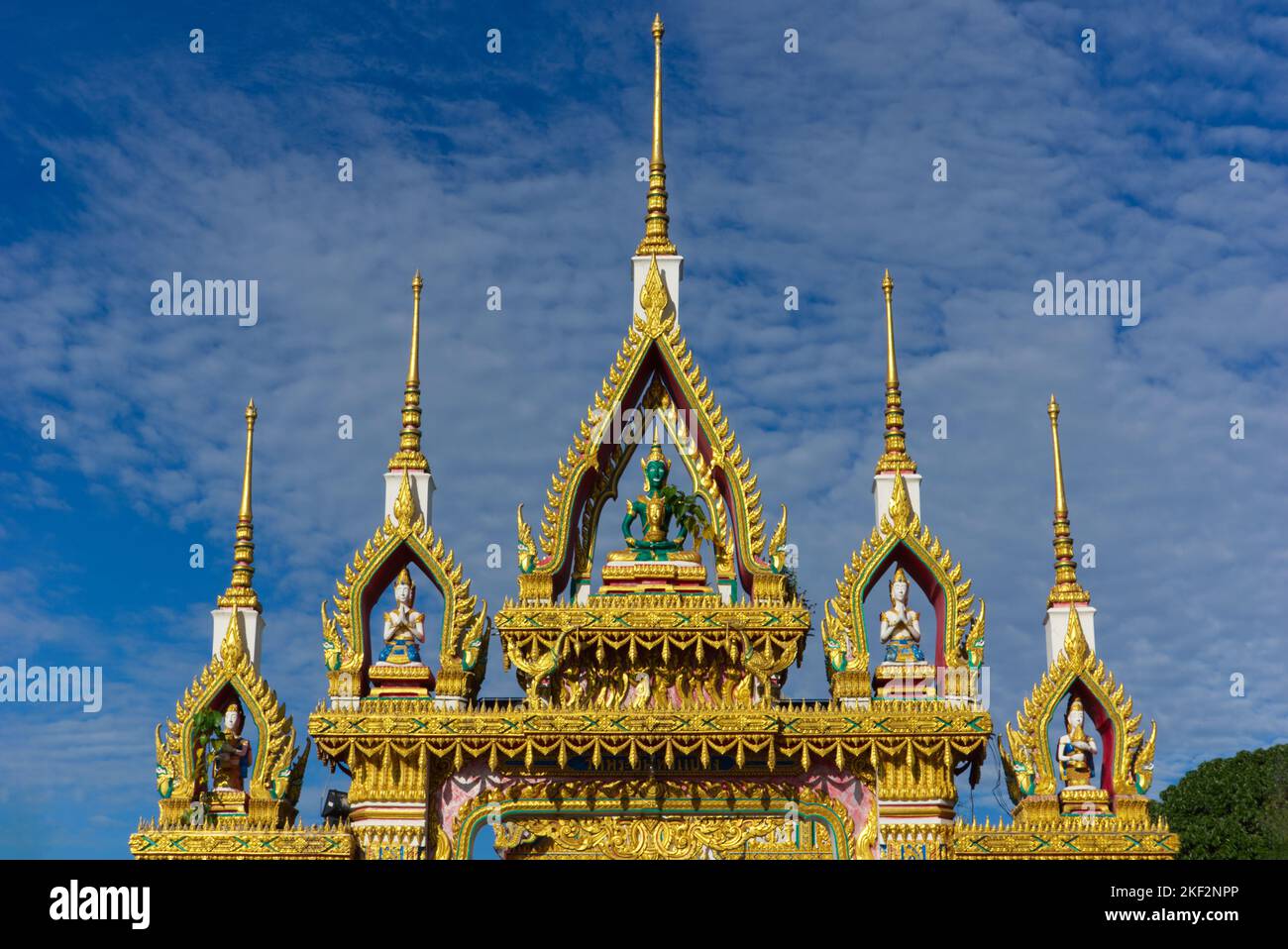 A Thailand temple detail view with gold leaf and a blue sky background ...