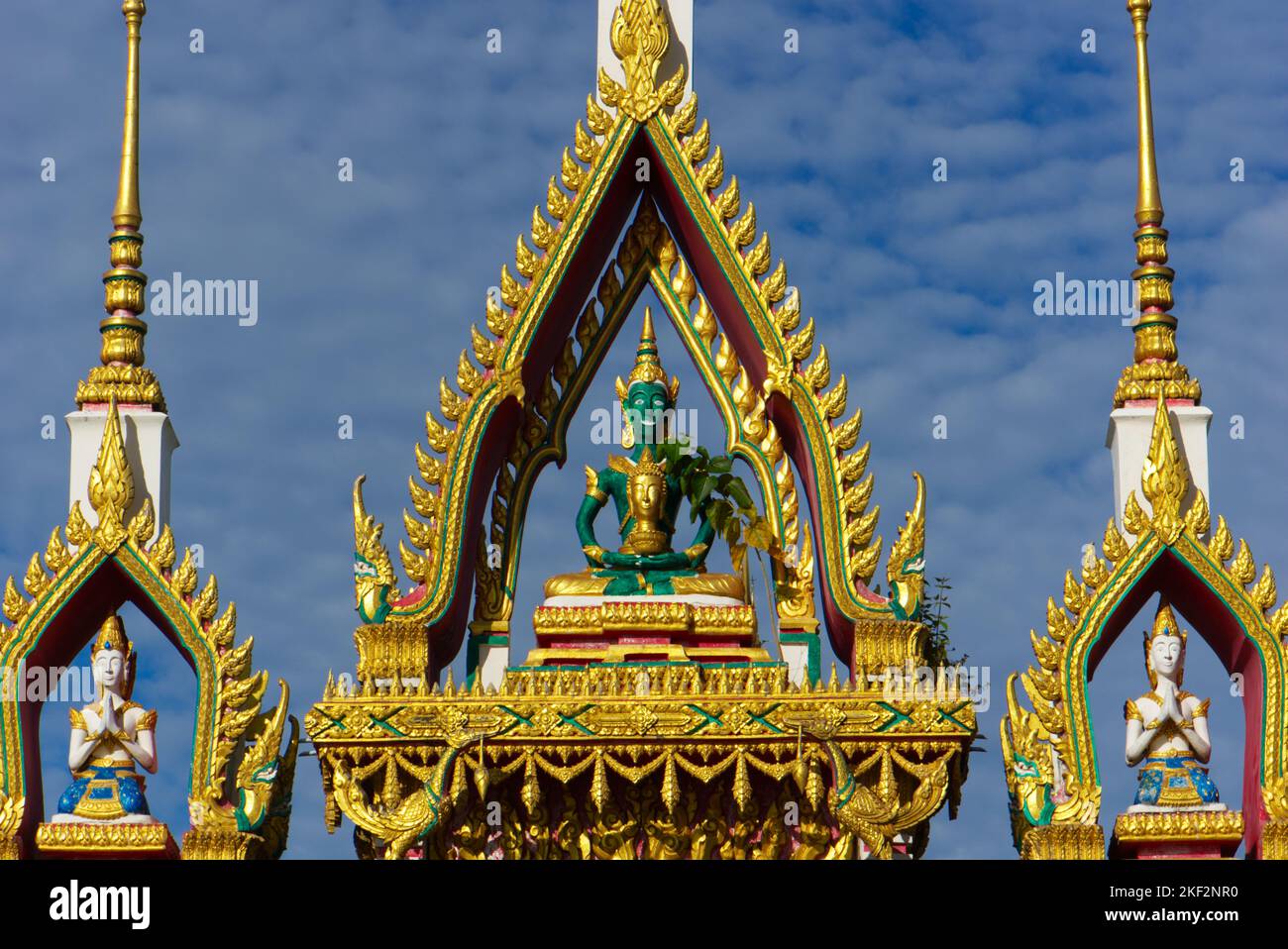 A Thailand temple detail view with gold leaf and a blue sky background ...