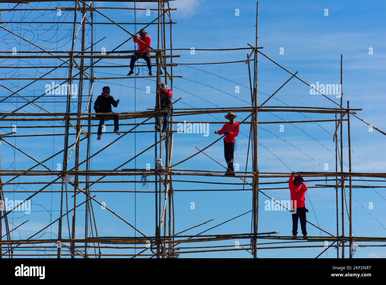 Men working together on bamboo scaffolding prepare for traditional Thai ...