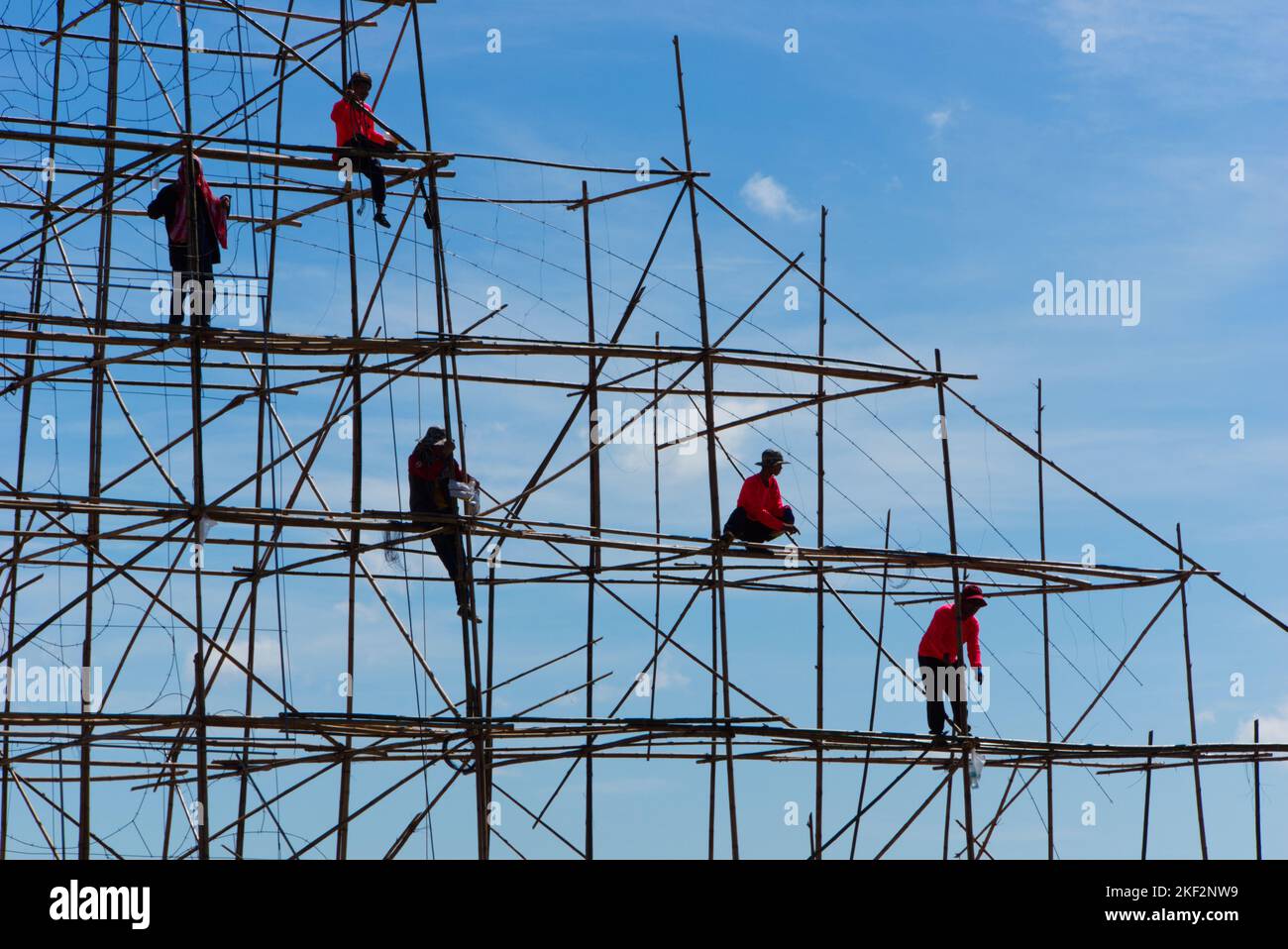 Men working together on bamboo scaffolding prepare for traditional Thai ...