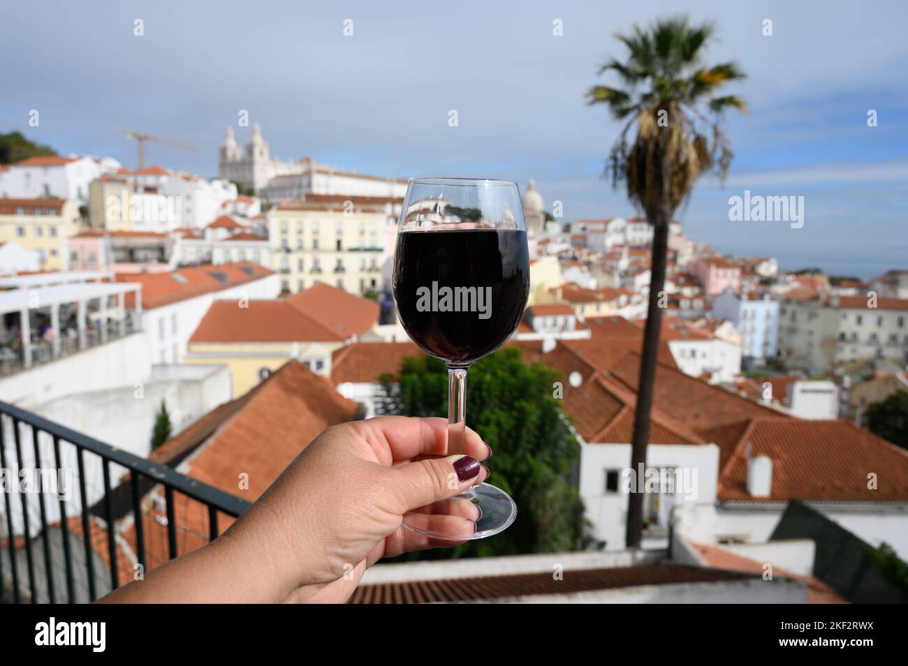 Hand with glass of dry red Portuguese wine in outdoor cafe at view ...