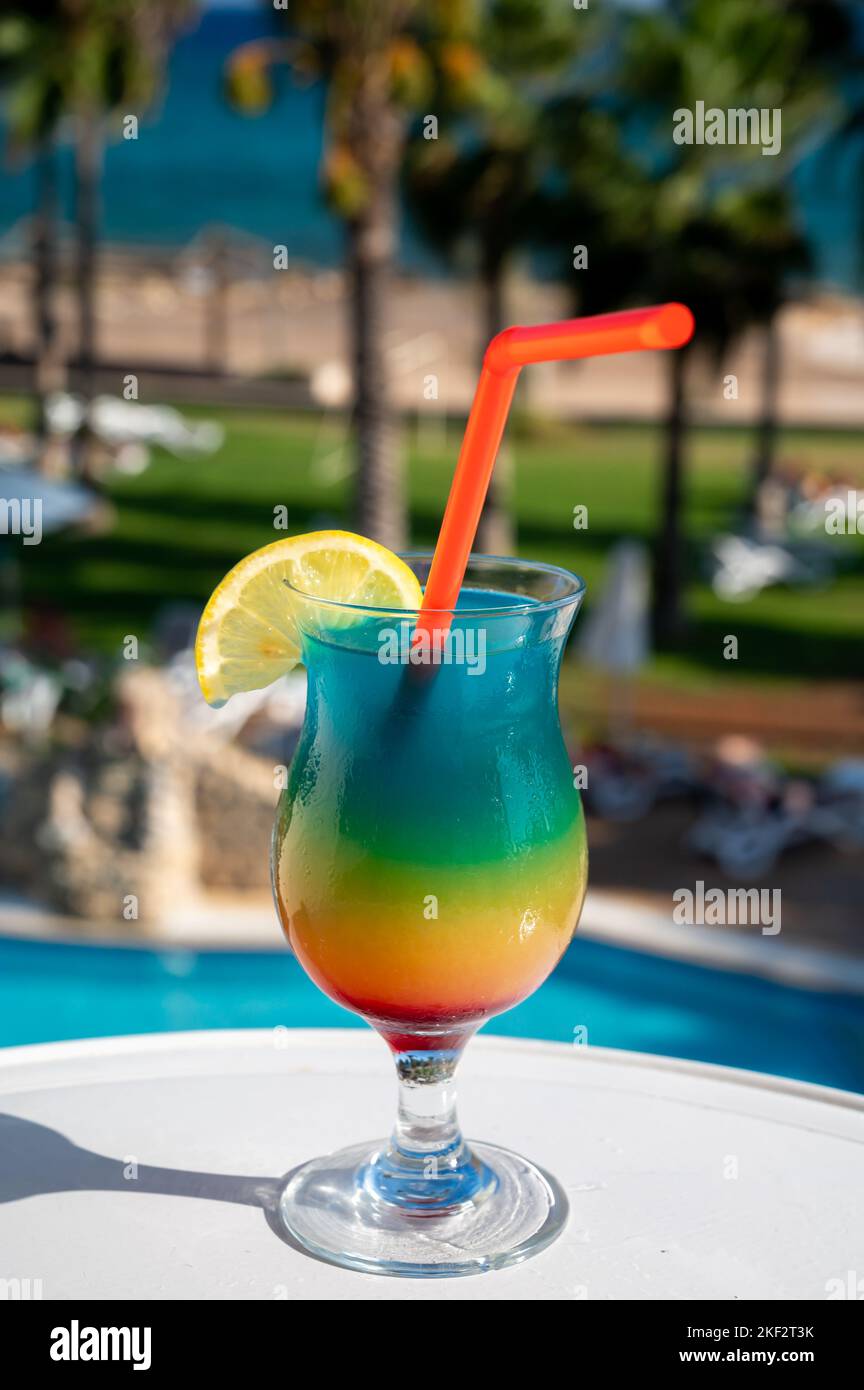 Colourful frozen Rainbow Paradise cocktail drink served in glass at ...