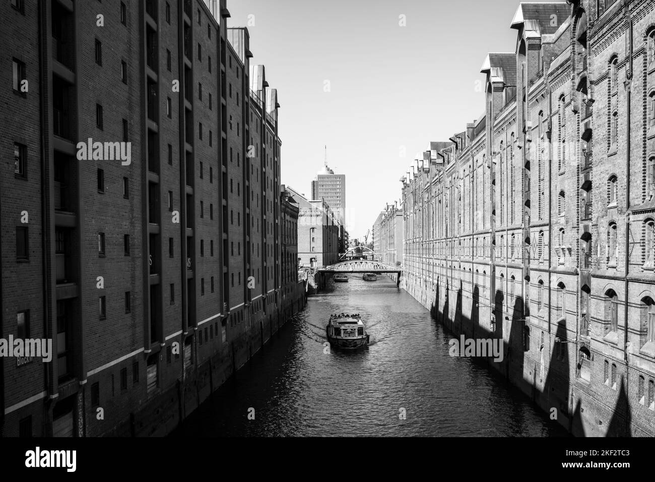 A gray-scale shot of boat in the river with building on the side in ...