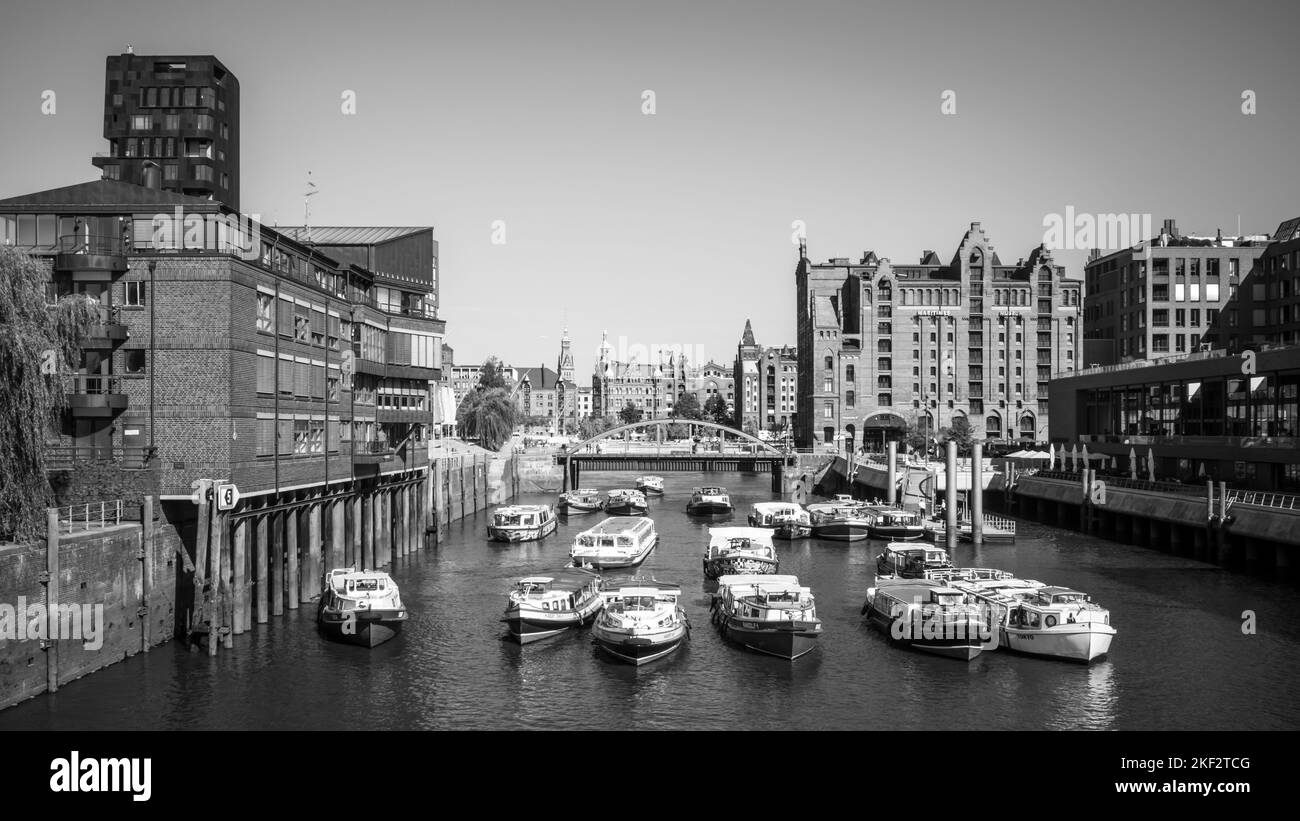 A gray-scale shot of boats in the river with building on the side in ...