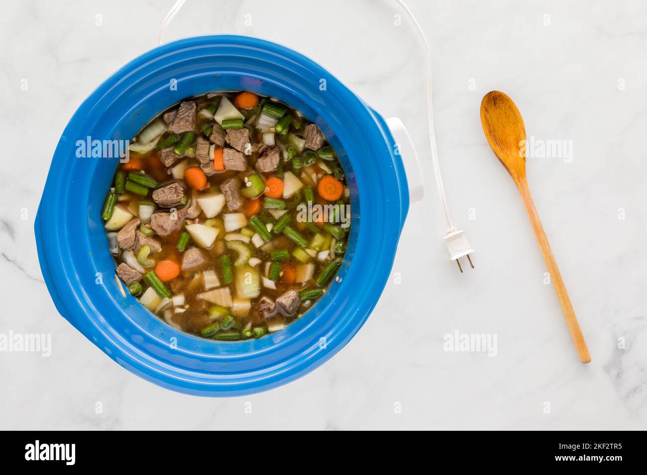 A crock pot filled with homemade prepared beef stew ready for cooking ...