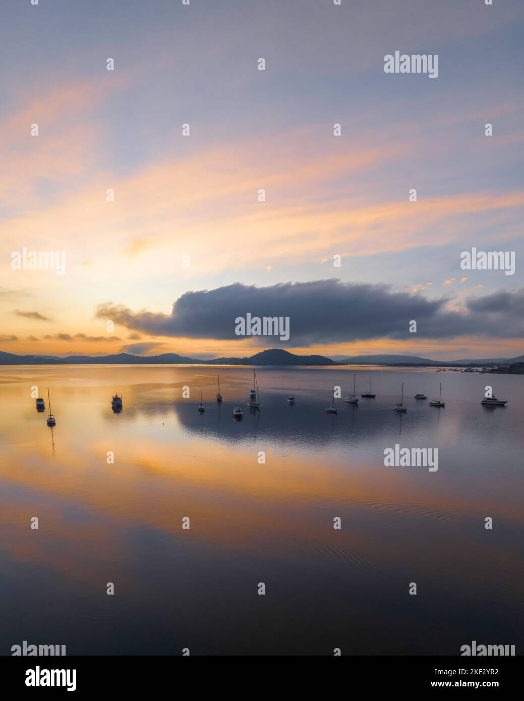 Soft and dreamy sunrise over Brisbane Water with clouds, fog and boats ...