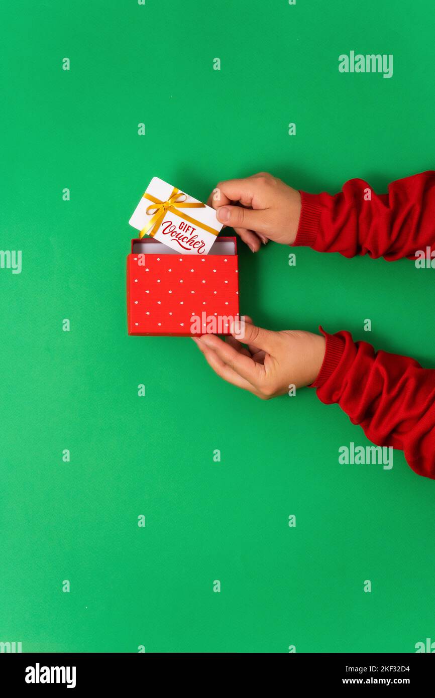 Female hands take out a gift voucher from a gift box, a modern gift for ...