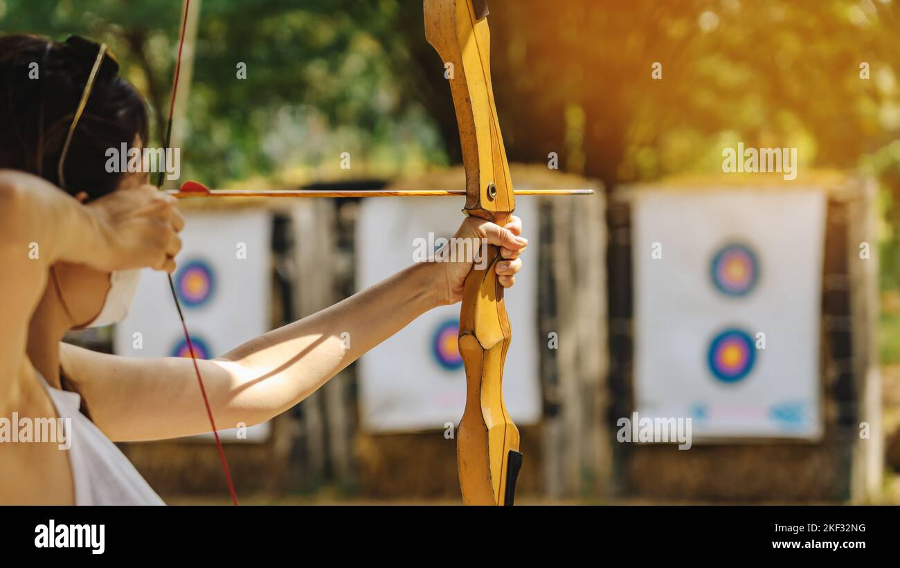 Hands of woman aims archery bow and arrow to colorful target in ...