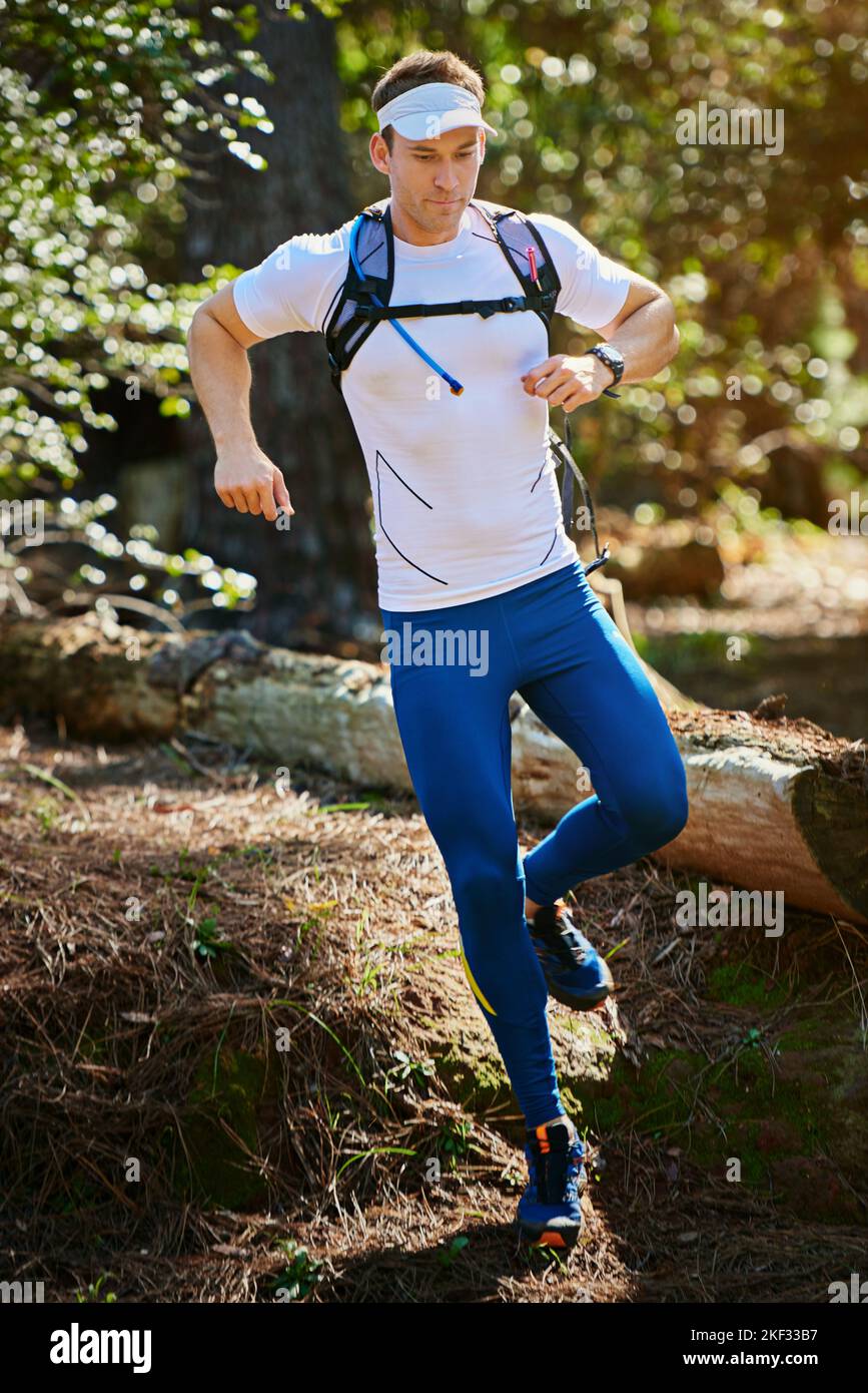 He loves a good trail run. a young man running along a nature trail ...
