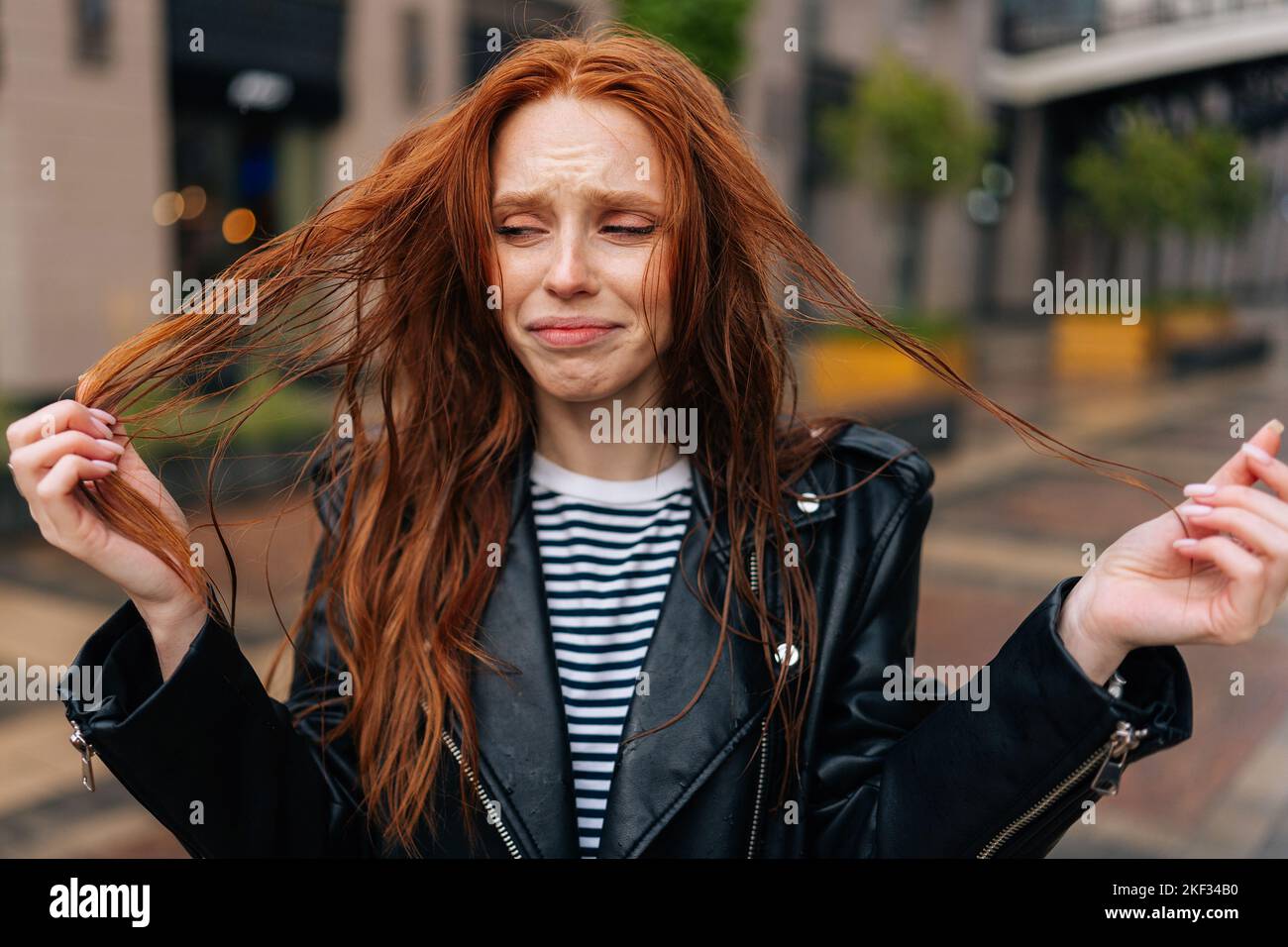 Portrait of sad attractive redhead young woman touching wet hair after ...