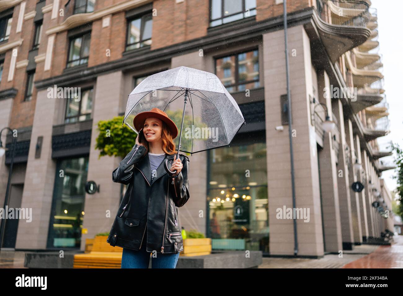 Low-angle view of happy young woman wearing elegant hat standing with ...