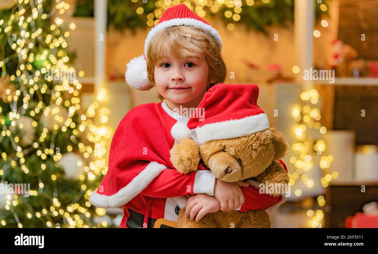 Dreamy child on Christmas eve. Kid in Santa hat embrace toy teddy bear ...