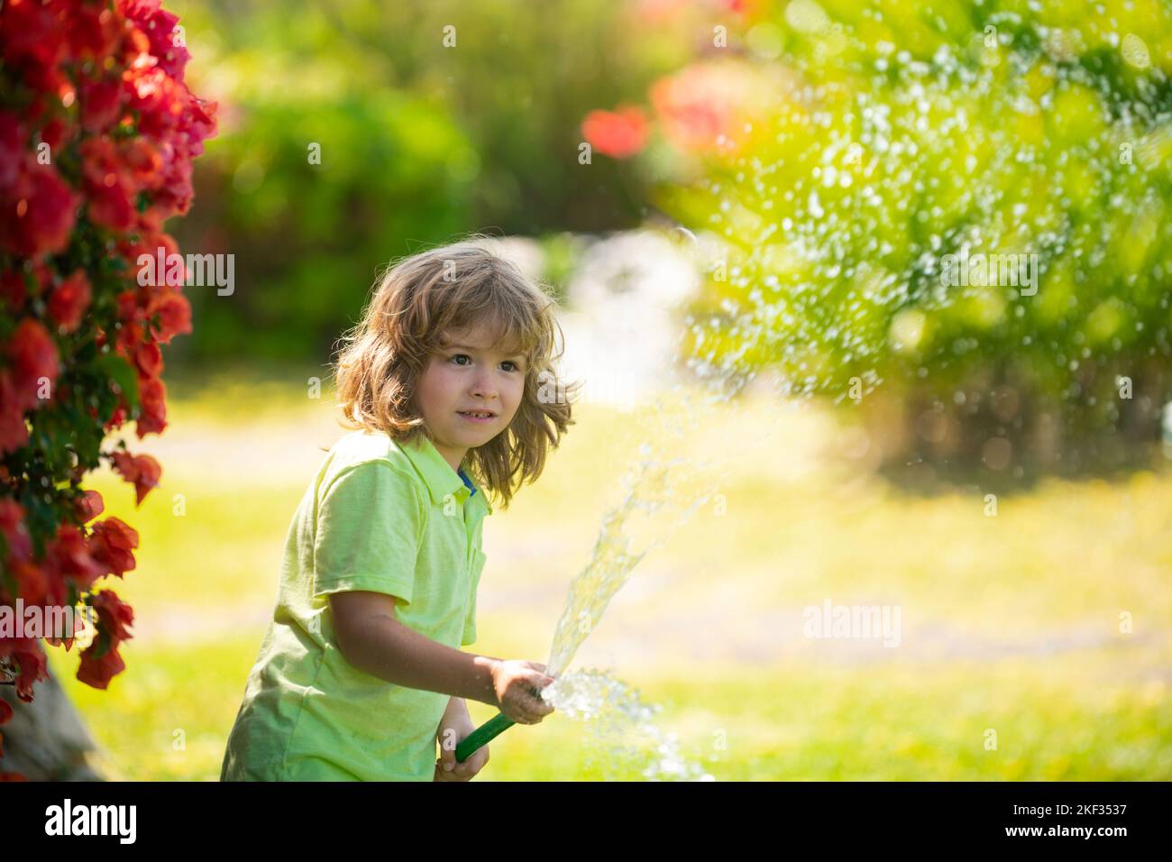 Happy kid boy pours water from a hose. American kids childhood. Child ...