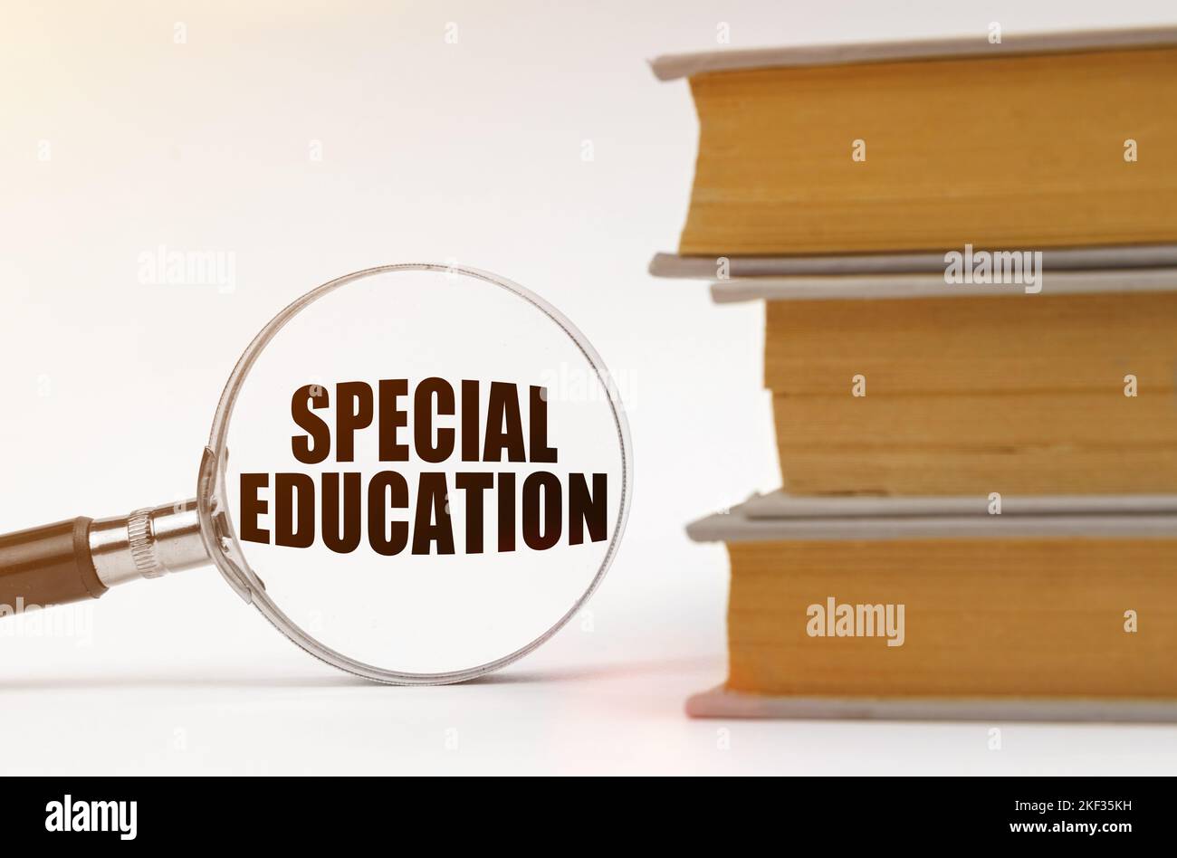Education concept. On a white background, books and a magnifying glass, inside which it is ...