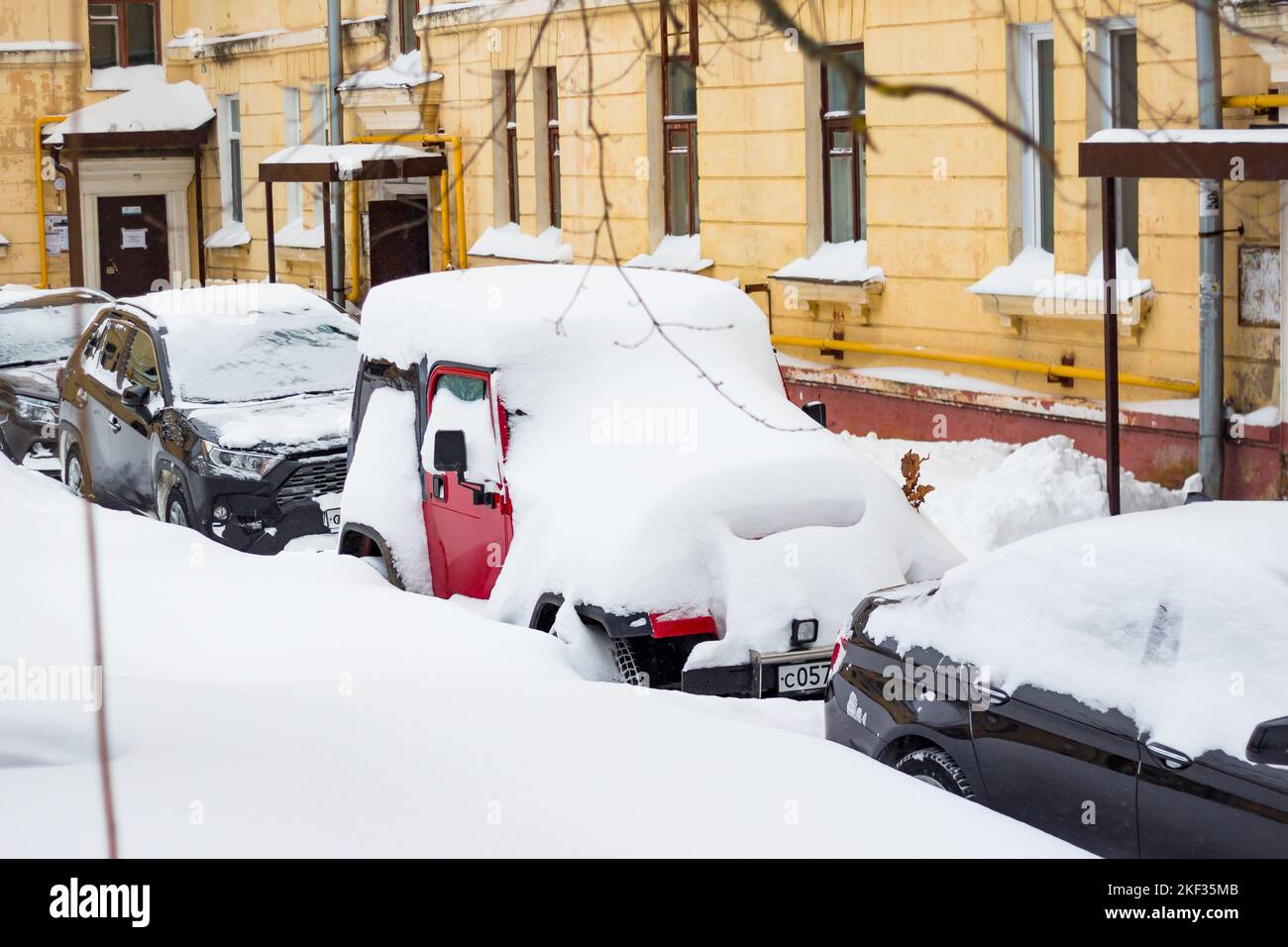 Cars parked in the courtyard of the house and covered with snow after a ...