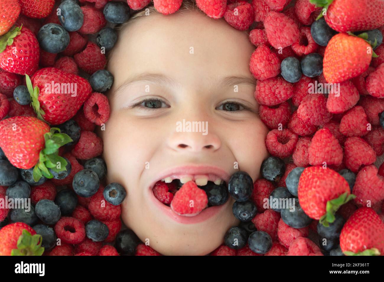 Vitamins from berrie. Kids face with fresh berries fruits. Assorted mix ...