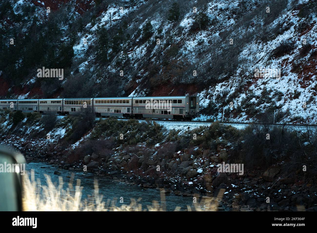 A beautiful shot of a train driving along a river flowing against ...